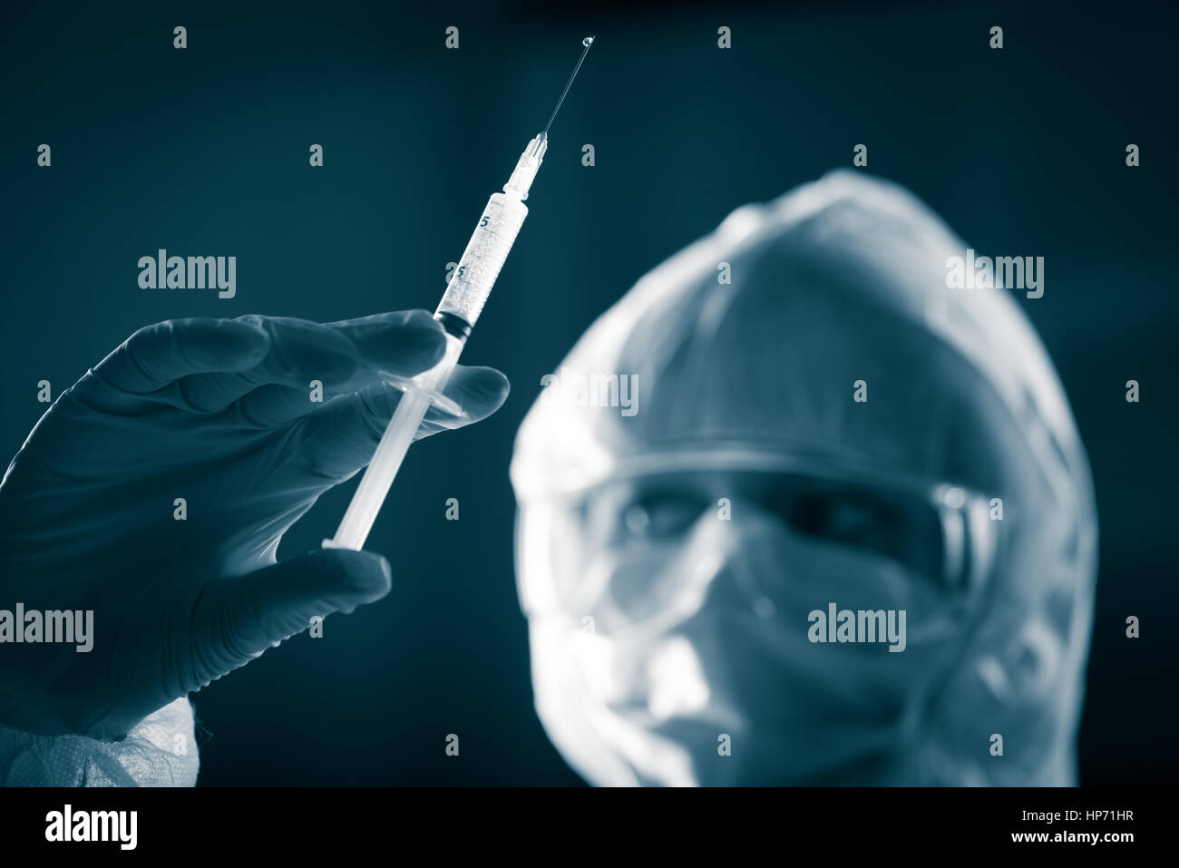Researcher in hazmat protective suit preparing a syringe for injection ...
