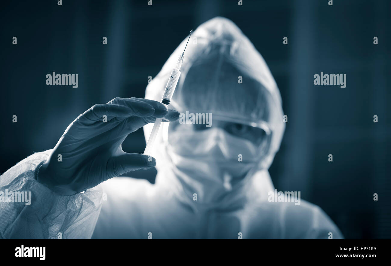 Researcher in hazmat protective suit preparing a syringe for injection ...