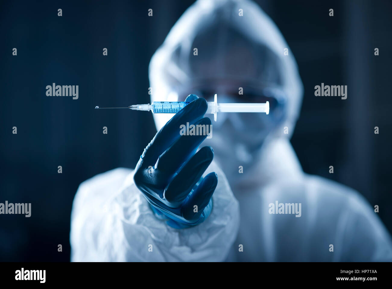 Researcher in hazmat protective suit preparing a syringe for injection ...