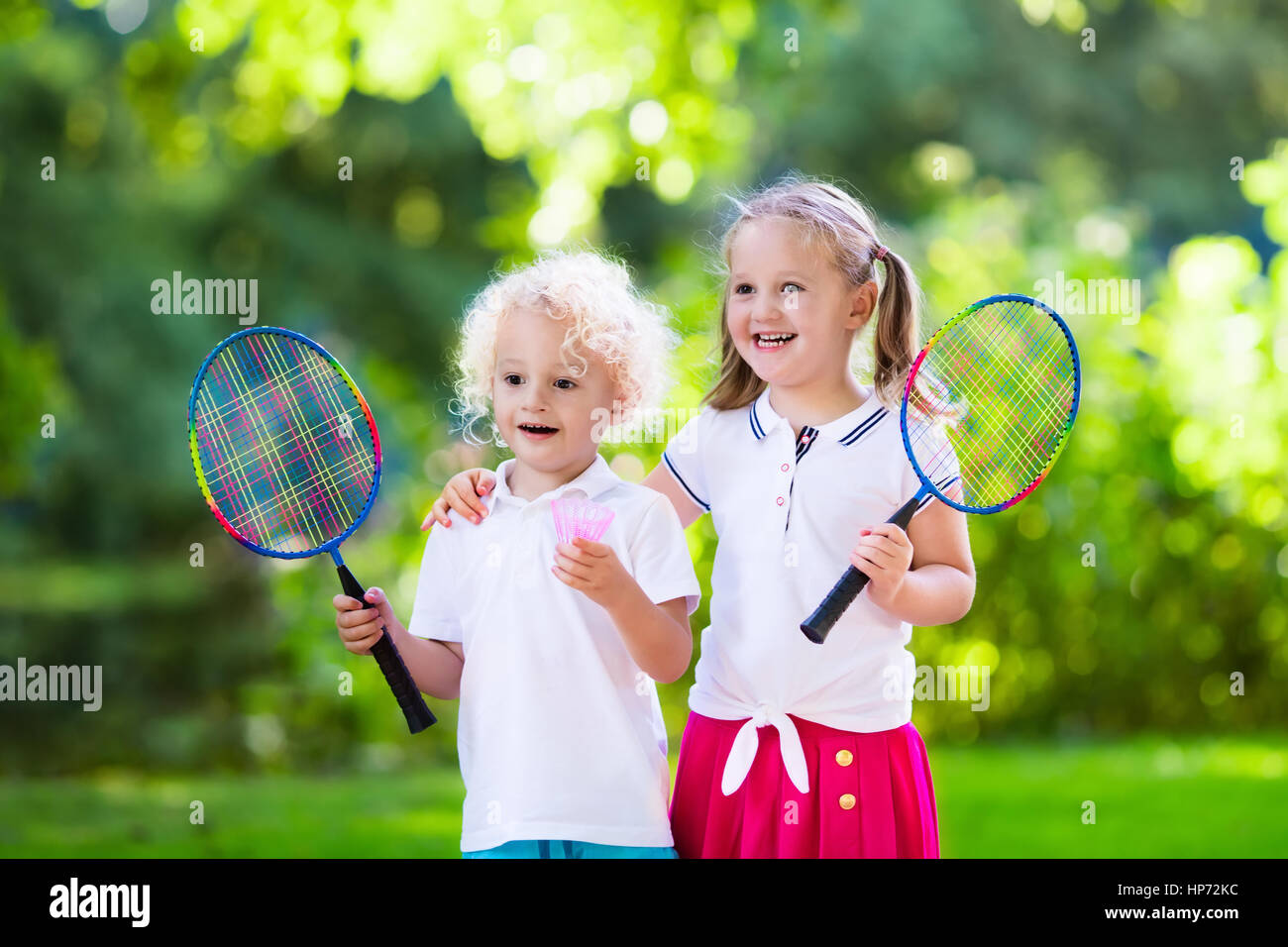 Active preschool girl and boy playing badminton in outdoor court in ...