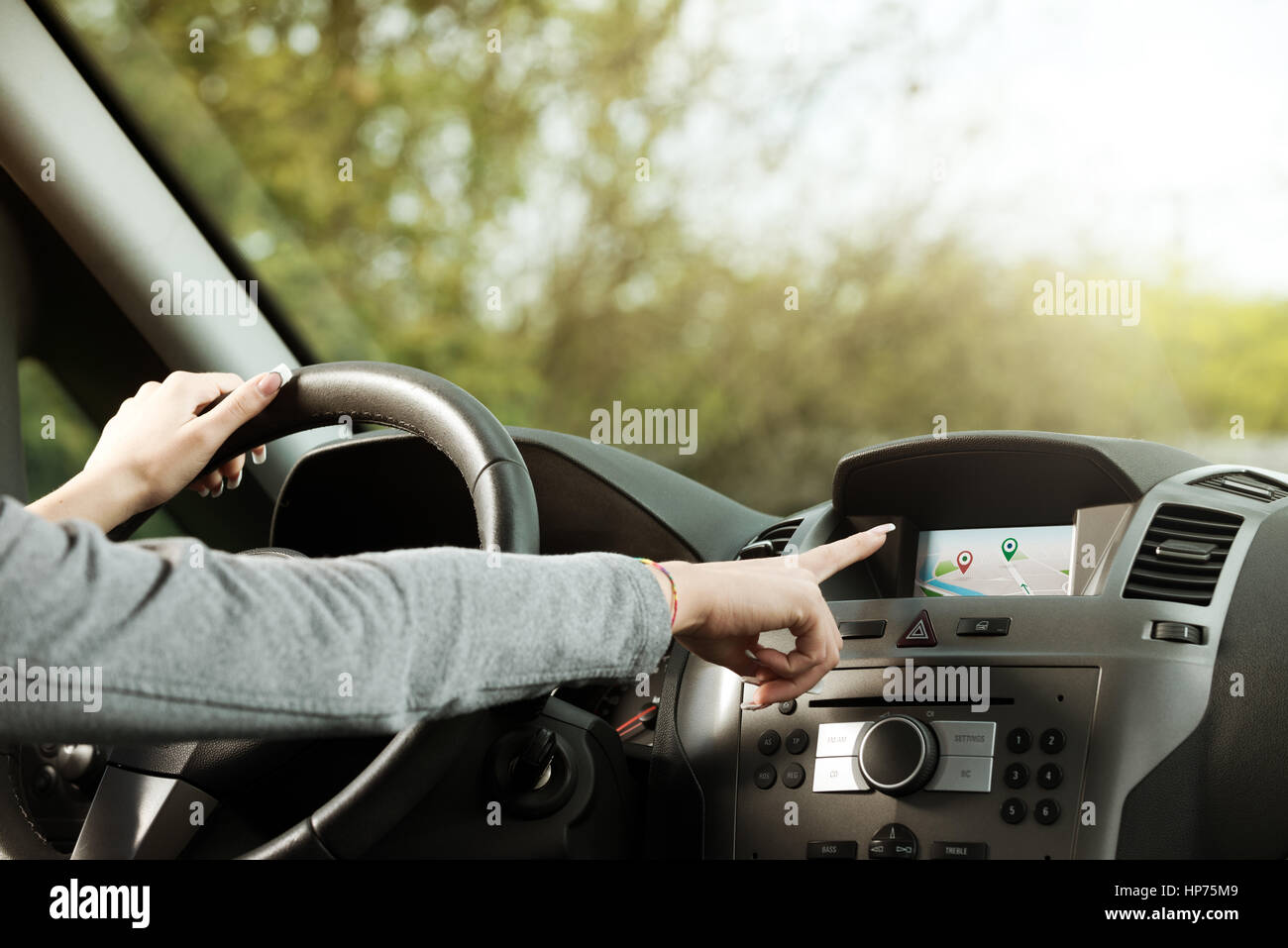 Woman driving and using touch screen gps panel for navigation in a car ...