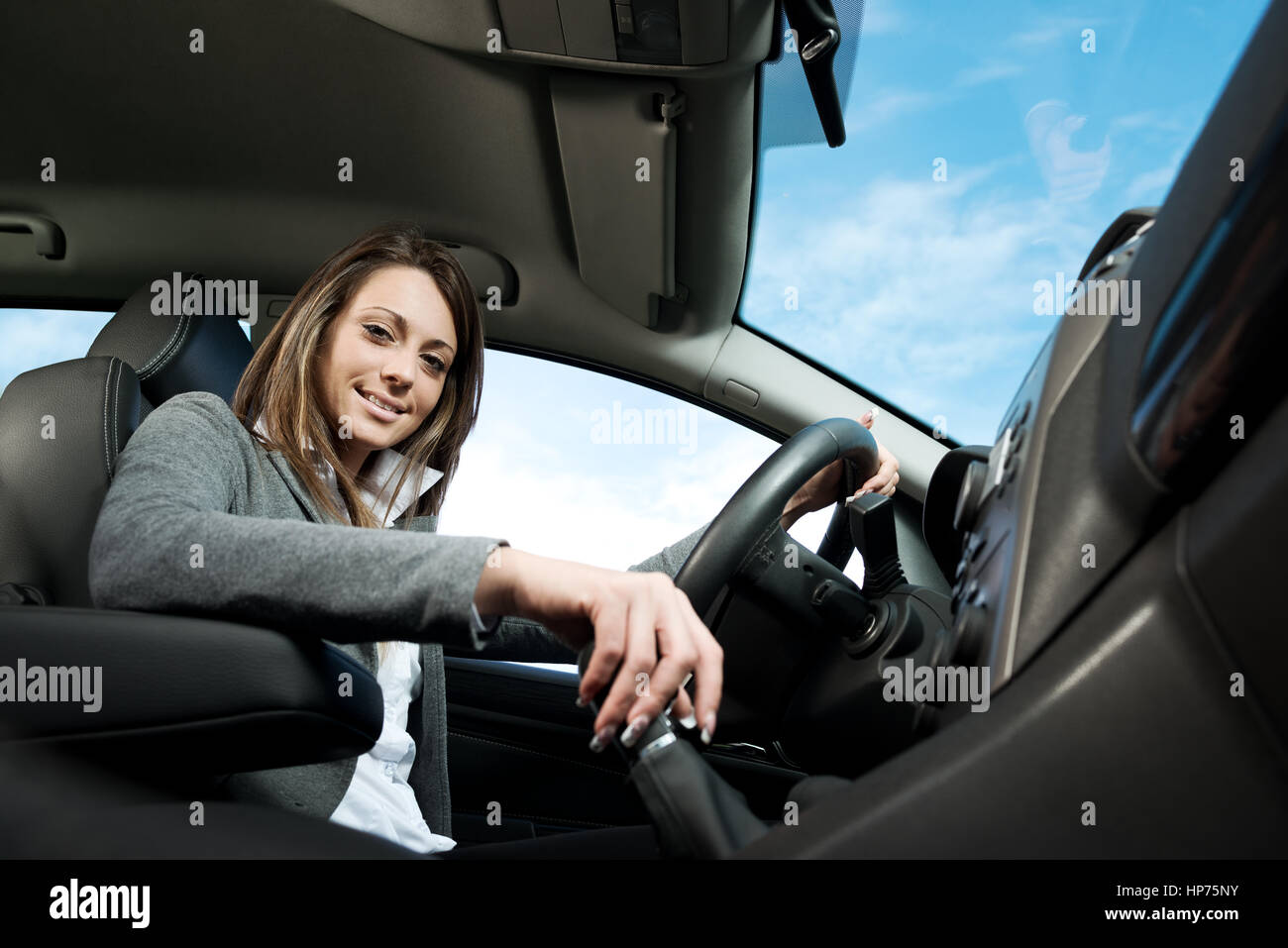 Young smiling woman driving her car with one hand on gear stick Stock ...