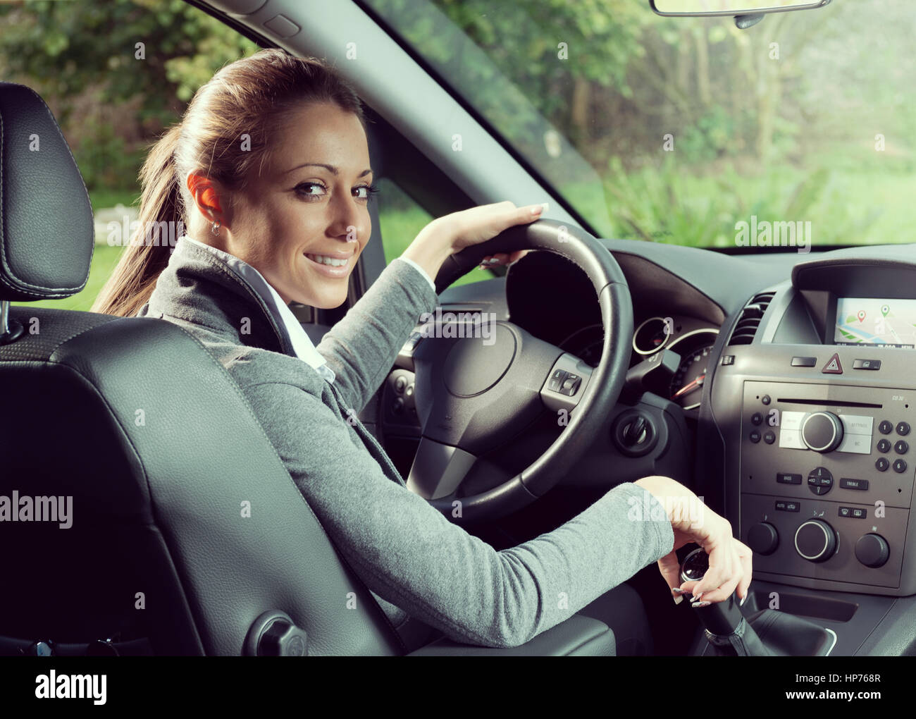 Smiling woman driving her car with one hand on gear stick Stock Photo ...