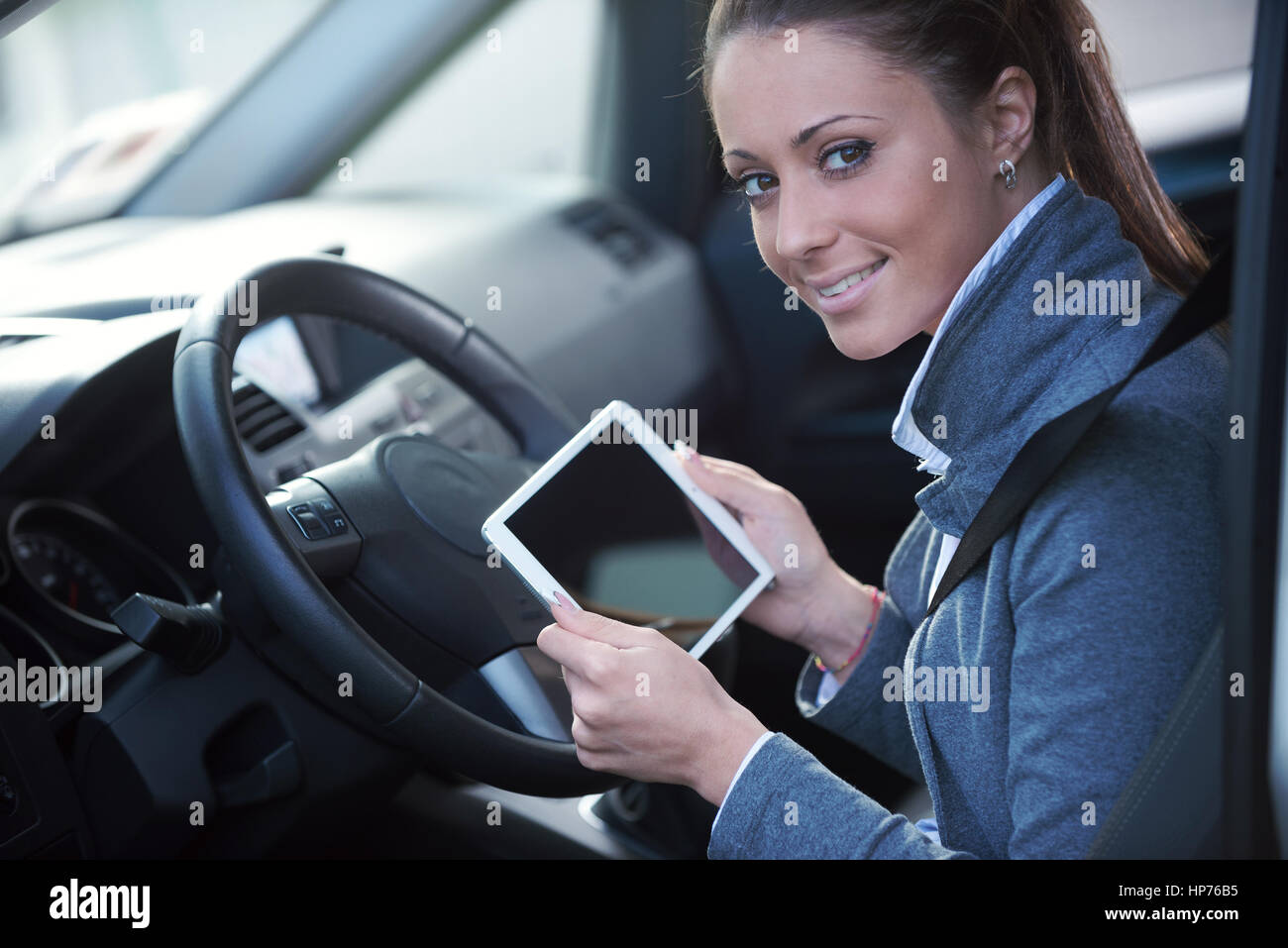 Young smiling woman in a car using a touch screen digital tablet Stock ...