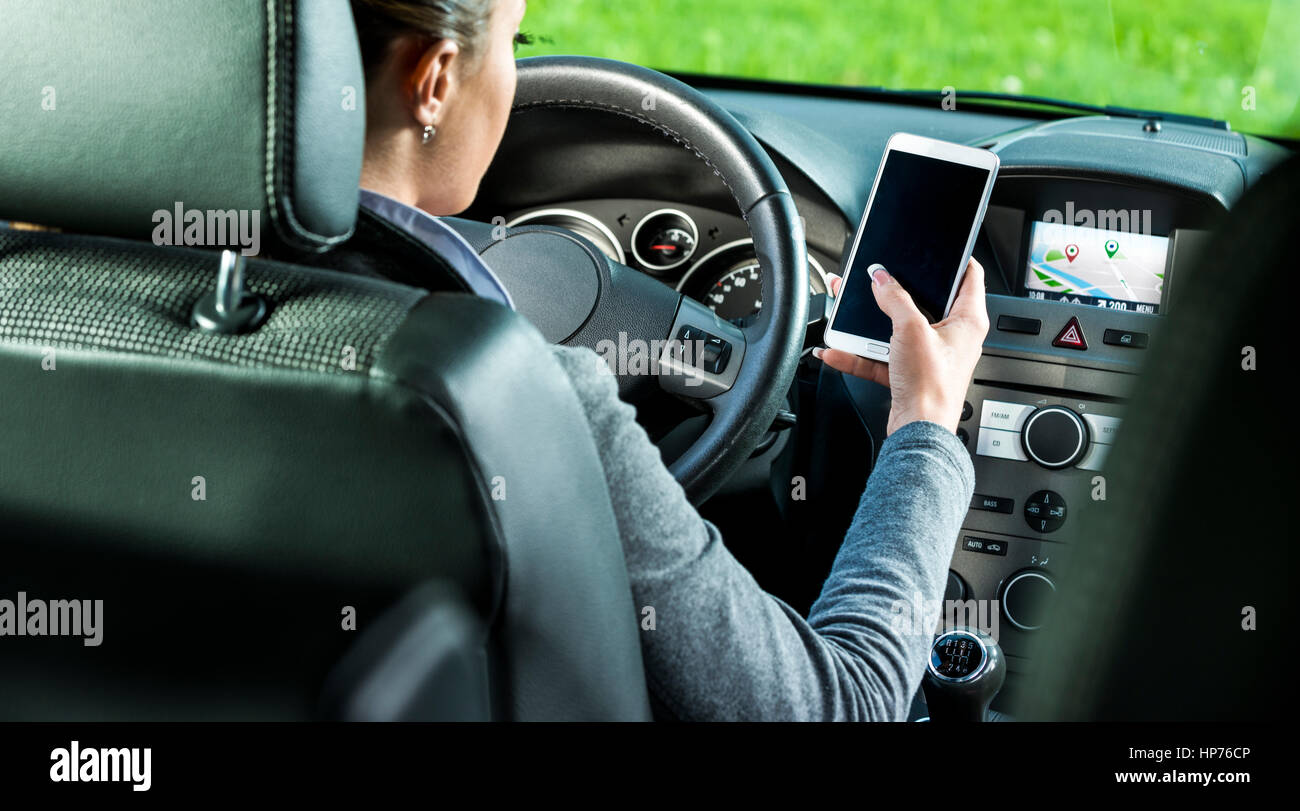 Young female driver using touch screen smartphone and gps navigation in ...