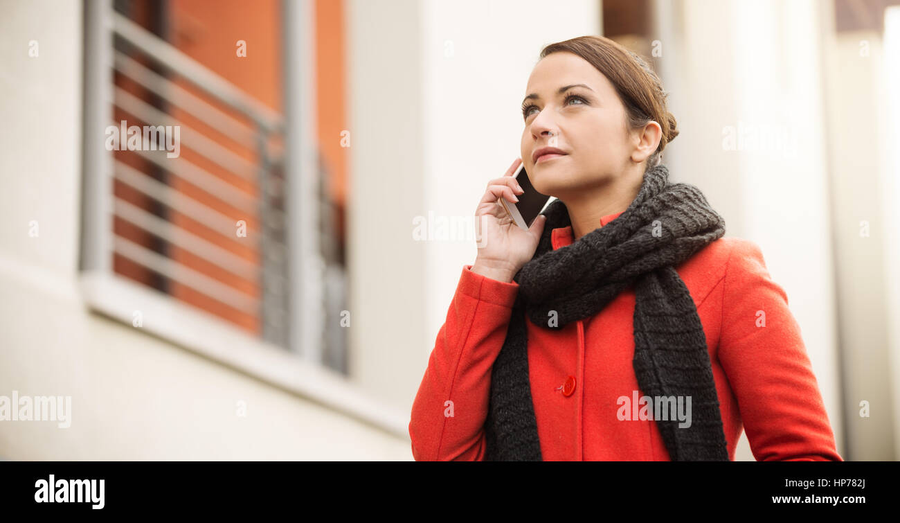 Smiling woman in the street having a phone call, city buildings on ...