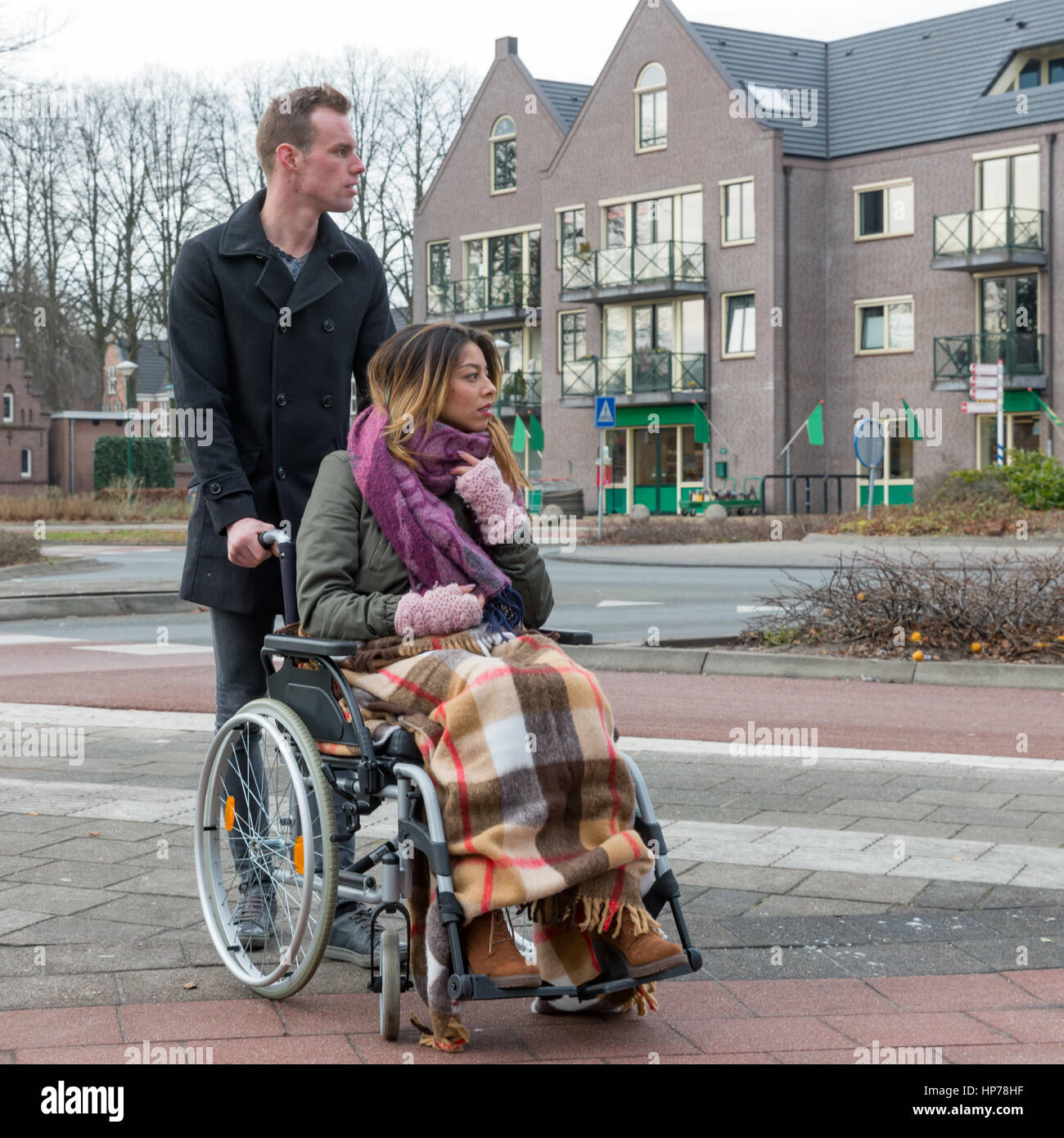Man pushing a woman in a wheelchair at a zebra crosssing in a Dutch ...