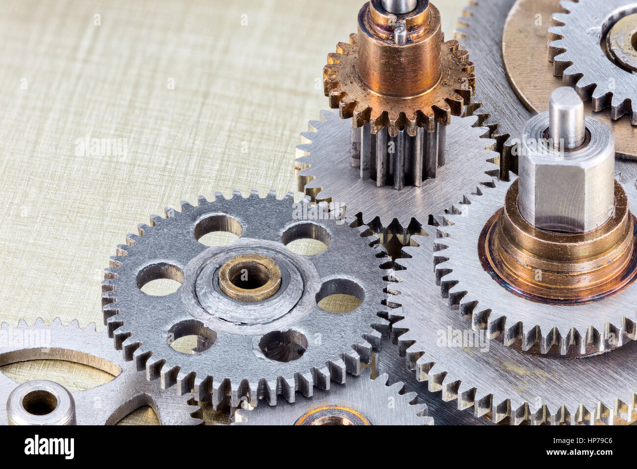 set of industrial cogwheels for machinery on brass metal background ...