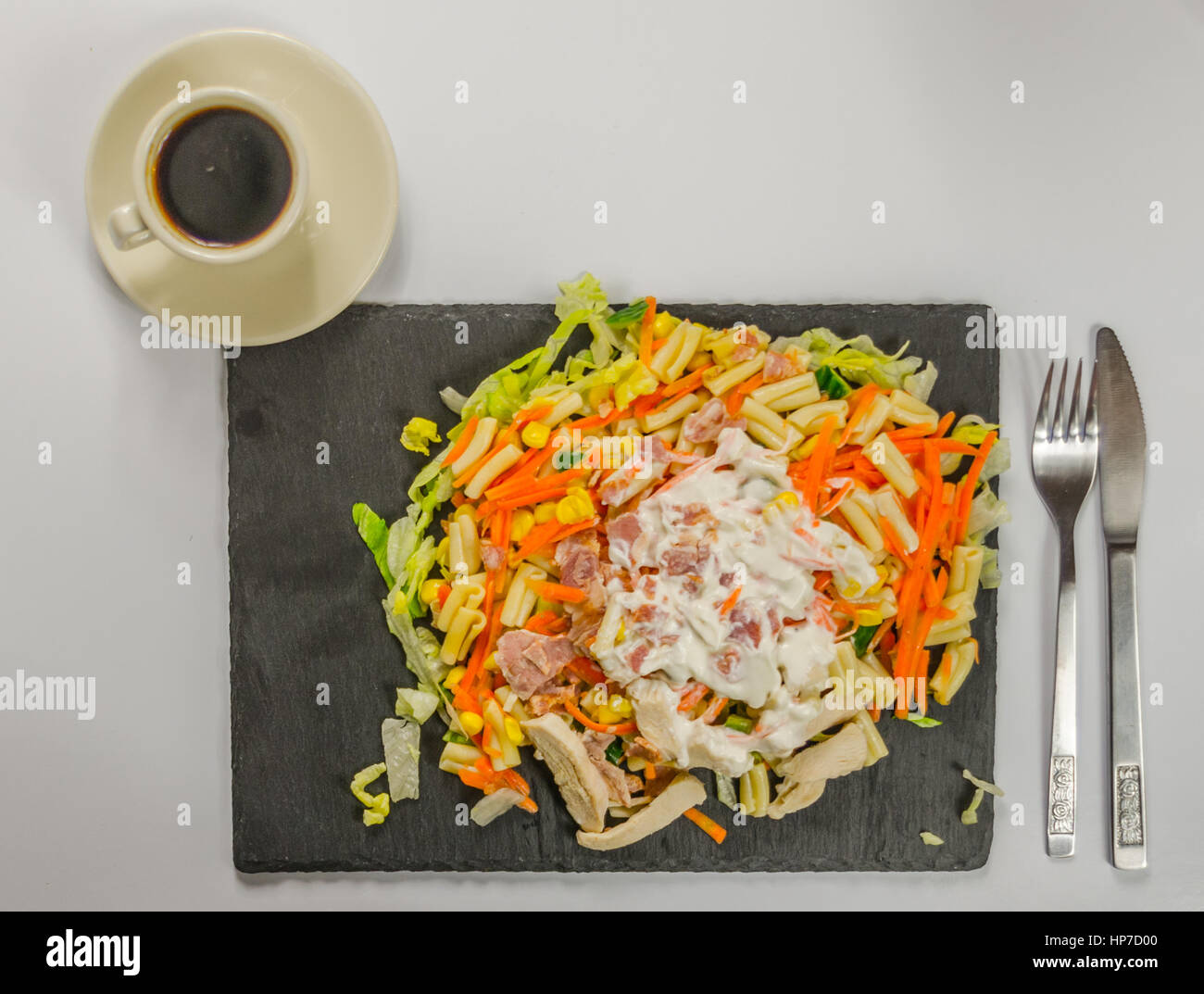 salad with chicken, bacon and pasta sauce logs on a black stone plate ...