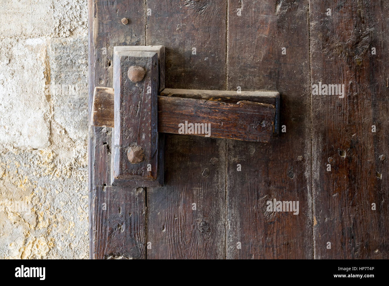 Front view closeup of a wooden aged latch over a wooden opened door ...
