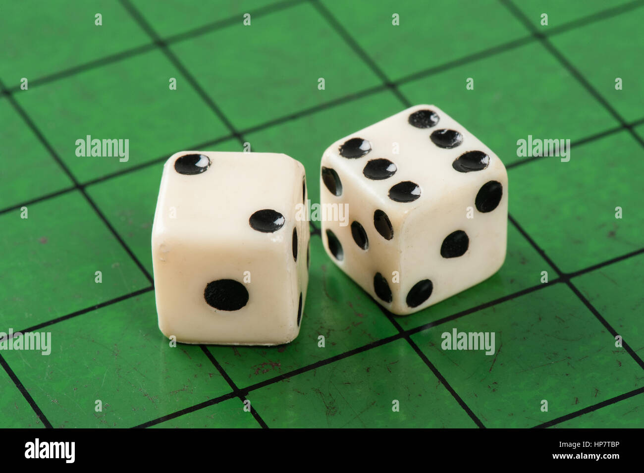 two old plastic dice on green background Stock Photo - Alamy