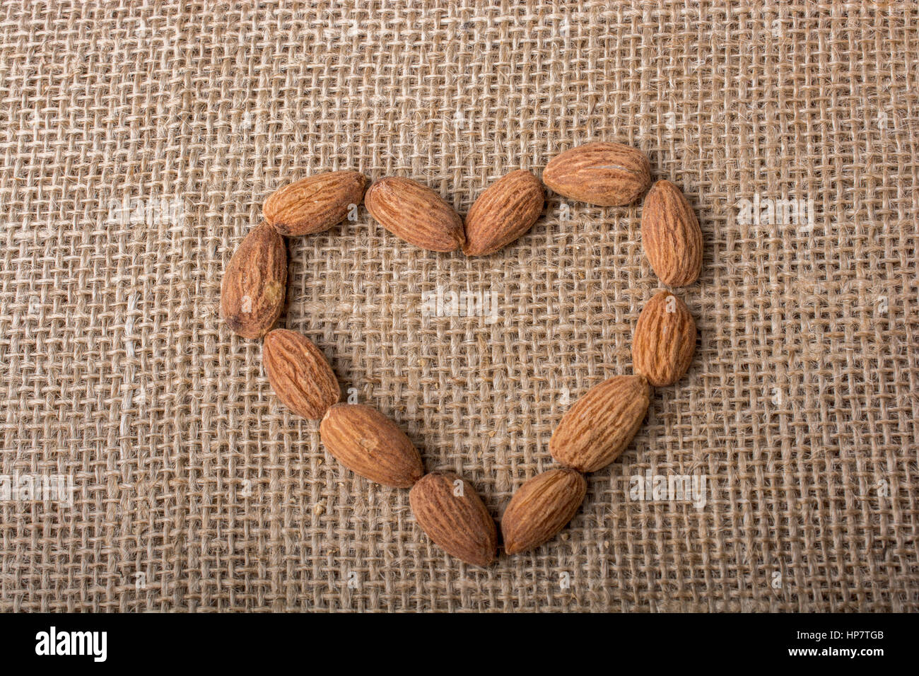 Almonds form a heart shape on canvas background Stock Photo - Alamy