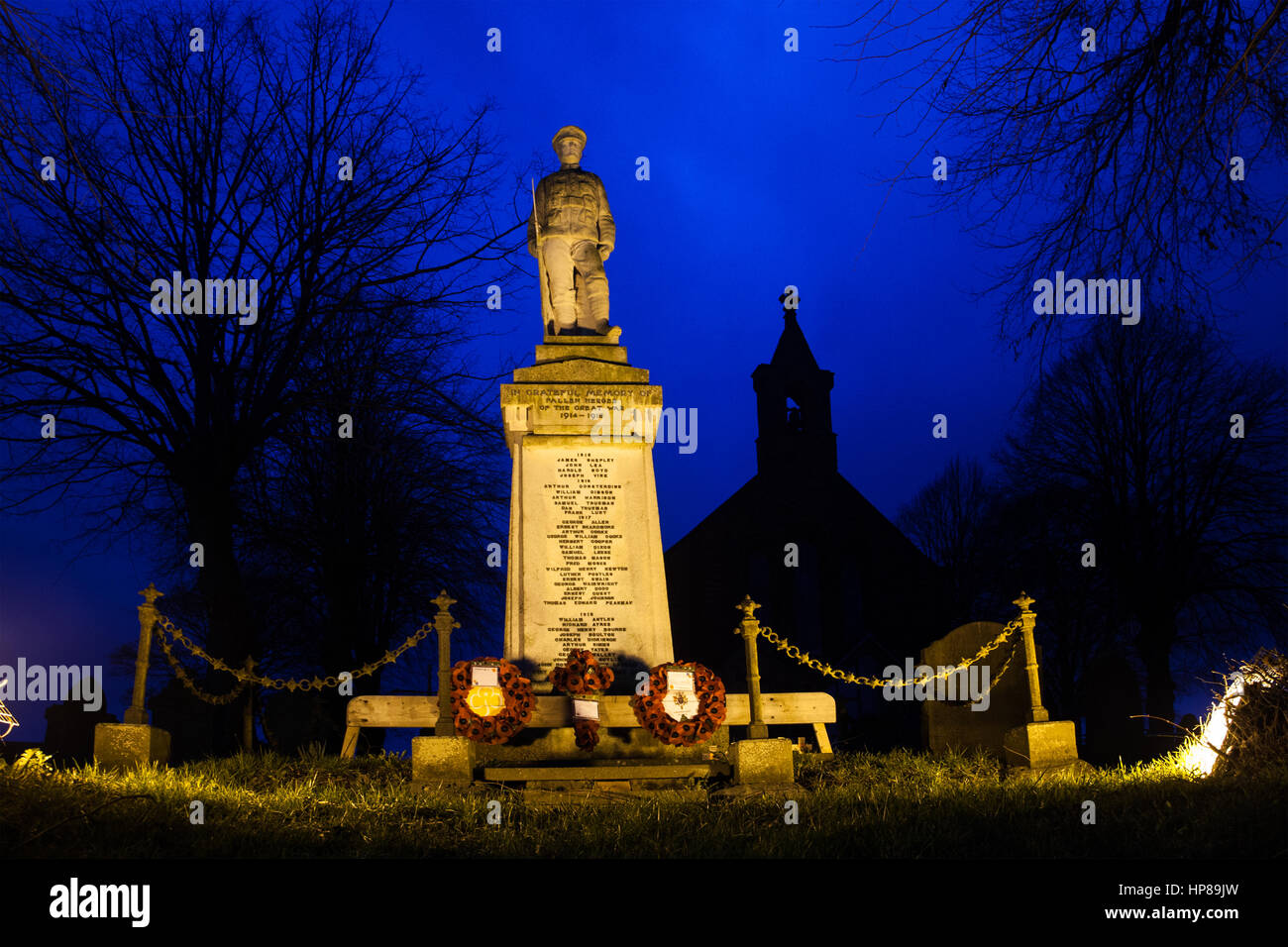 Floodlit war memorial in front of a silhouette of Christ church ...