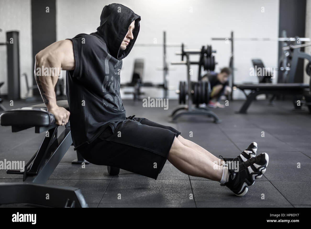 Active man with heavy muscles does lifting on the bench in the gym. He ...