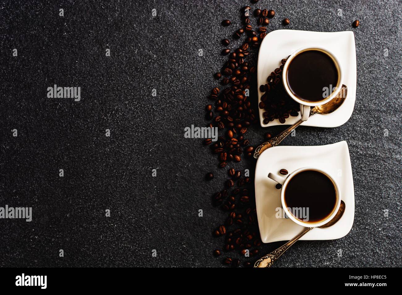 Two white cups of coffee with coffee bean on black stone background ...
