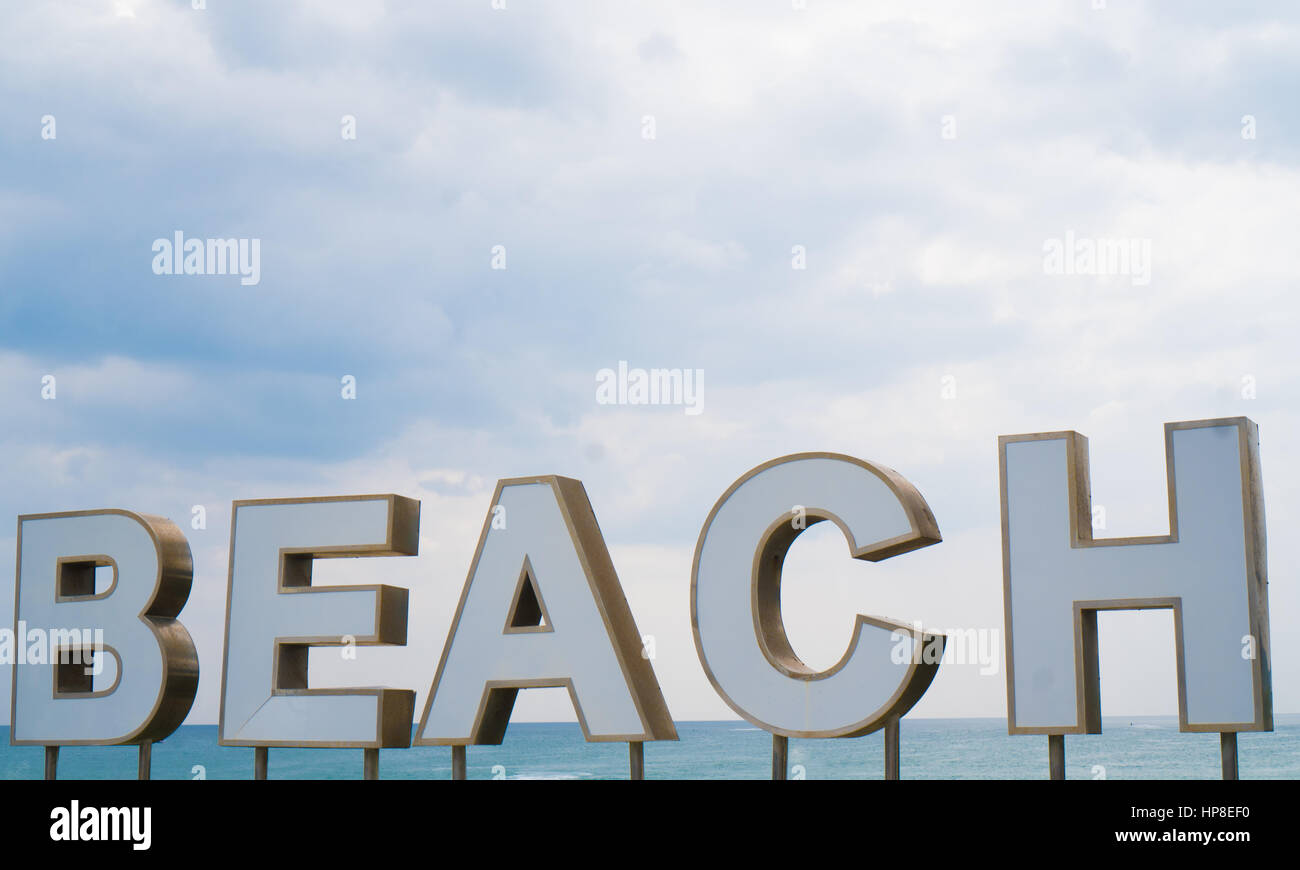 Big white and gold "Beach" sign over blue sea and sky background Stock ...