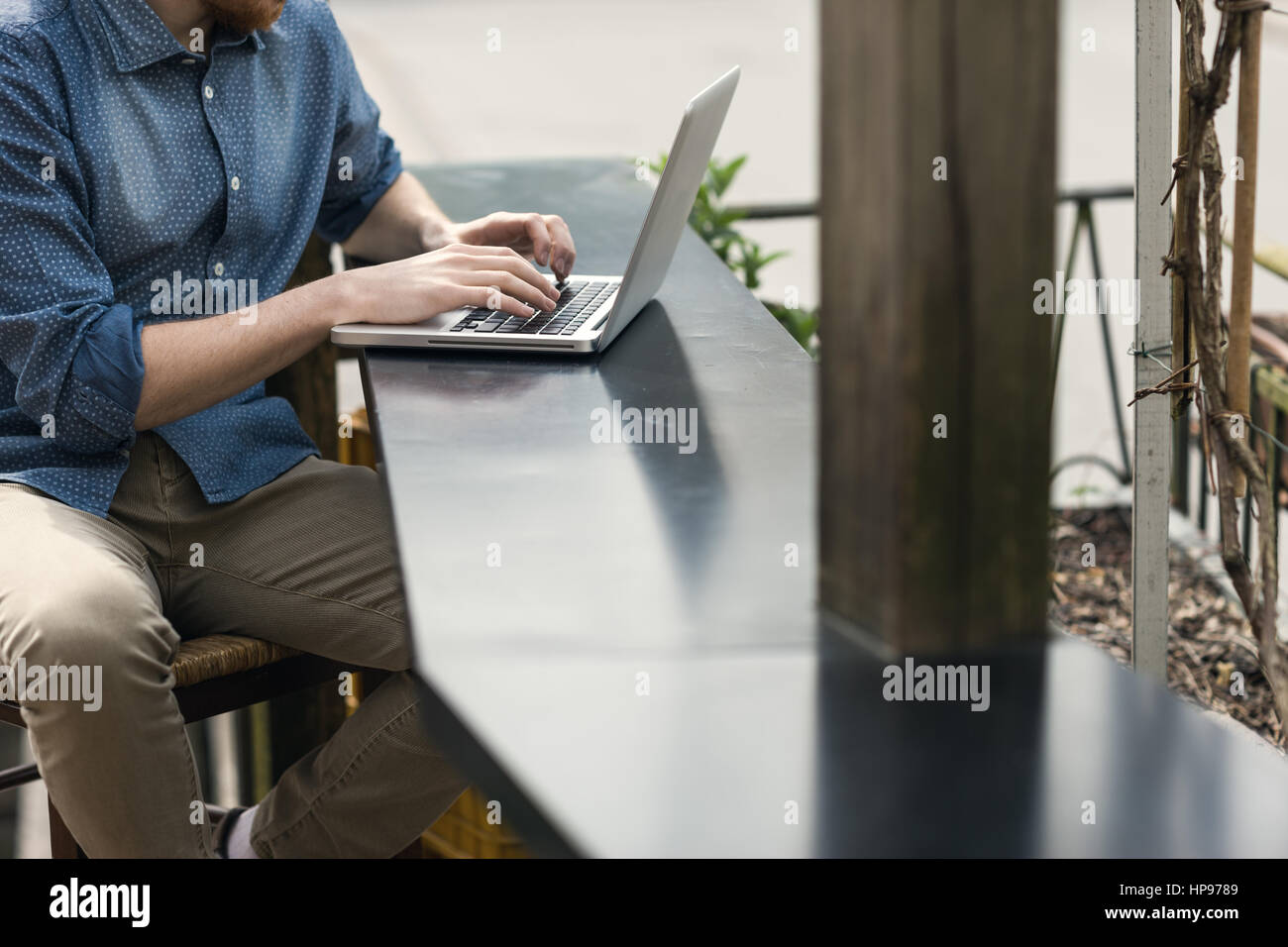 Unrecognizable man using a modern portable computer on an outdoor table ...