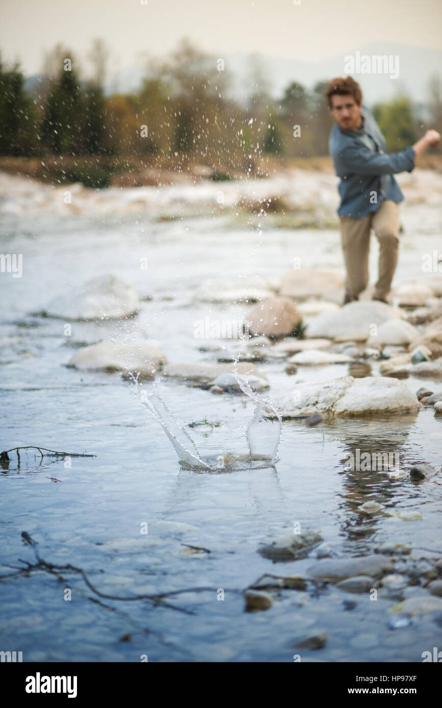 Young man throwing stones in the river and water splash, nature and ...