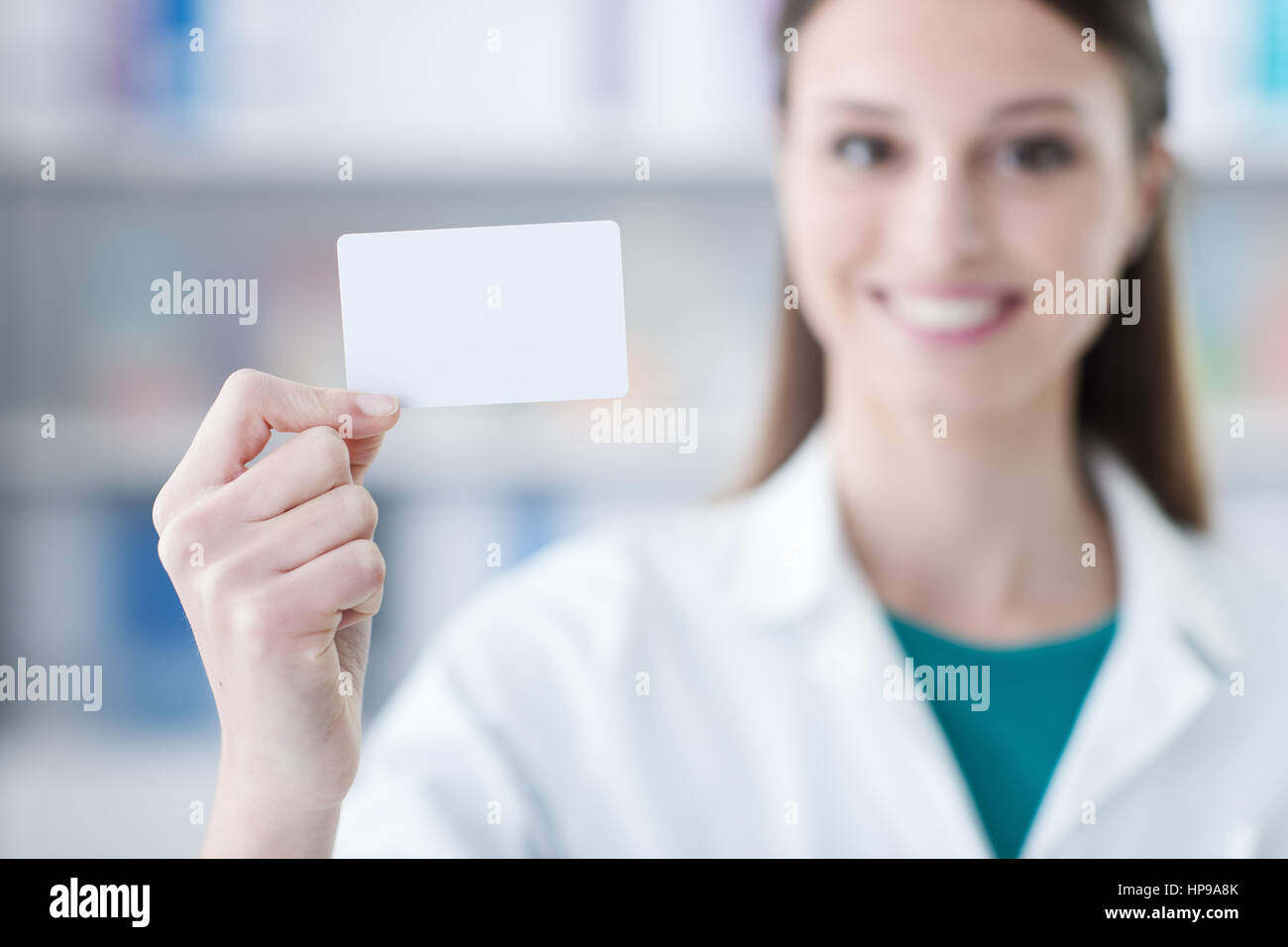 Smiling young female doctor holding an empty business card, healthcare ...