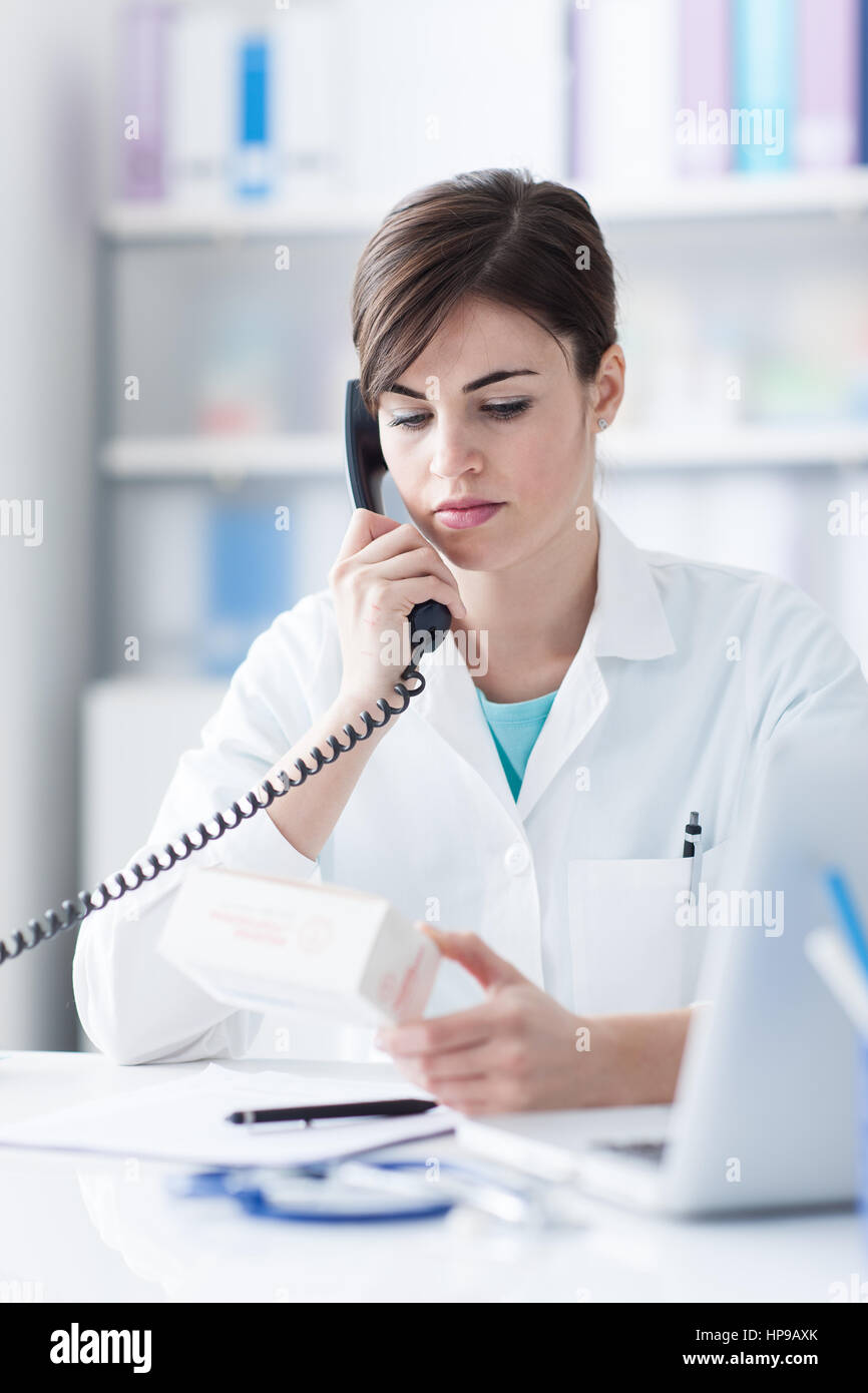 Young female doctor working at office desk, answering phone calls and ...