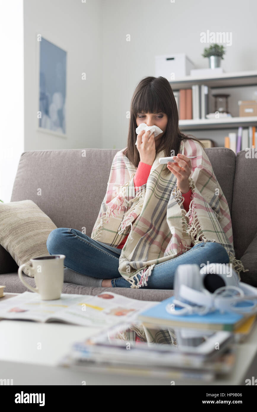Sick woman with cold and flu, she is resting on the sofa at home and ...