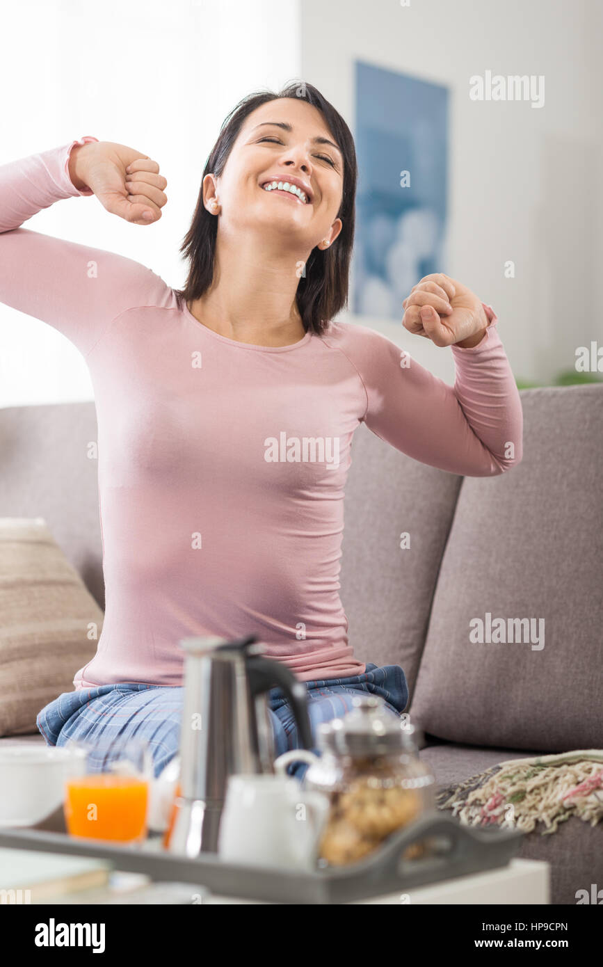 Sleepy young woman waking up on the sofa in the morning after a bad ...