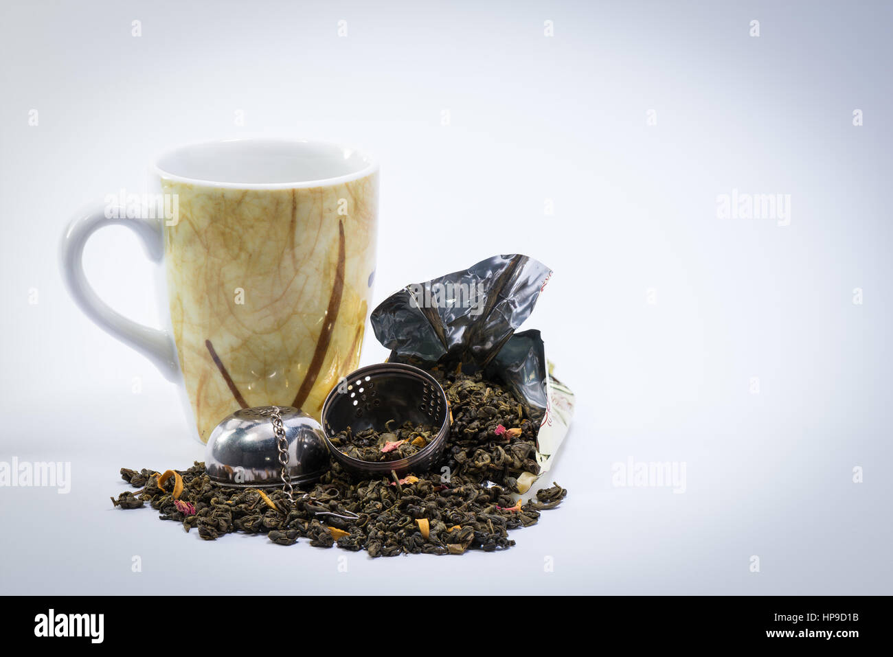 A nice Mug and an open infuser with mango green tea on a white ...
