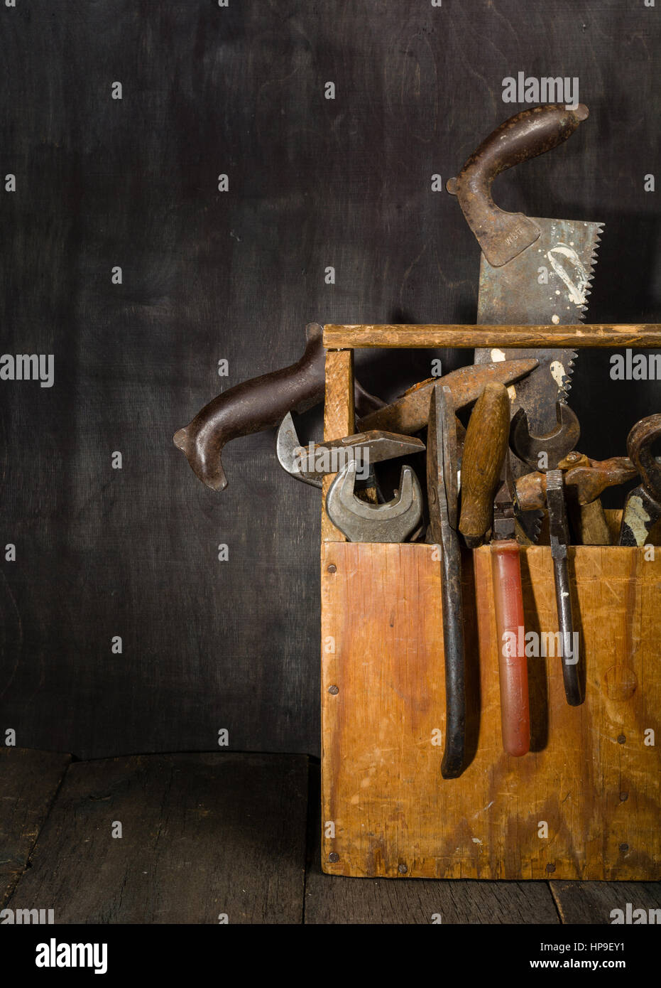 Old used tools in the toolbox. Dark background. spot lighting. Wooden ...