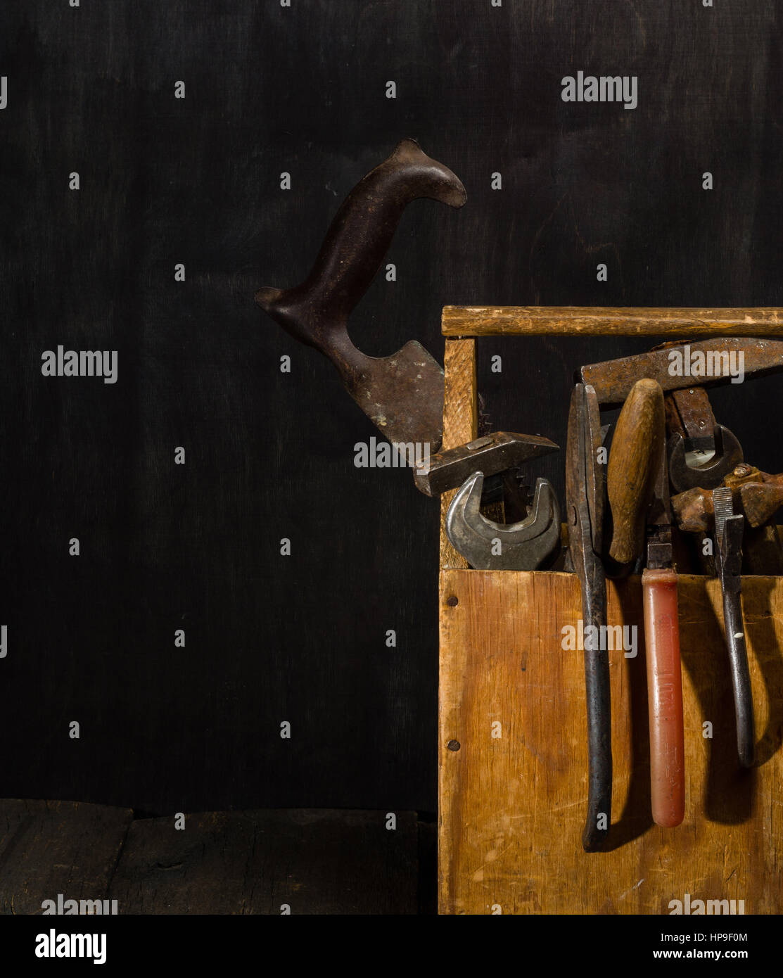 Old used tools in the toolbox. Dark background. spot lighting. Wooden ...