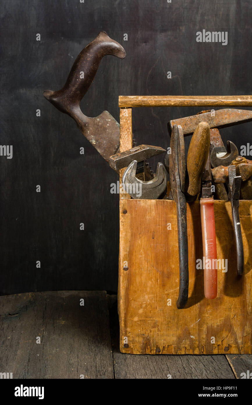 Old used tools in the toolbox. Dark background. spot lighting. Wooden ...