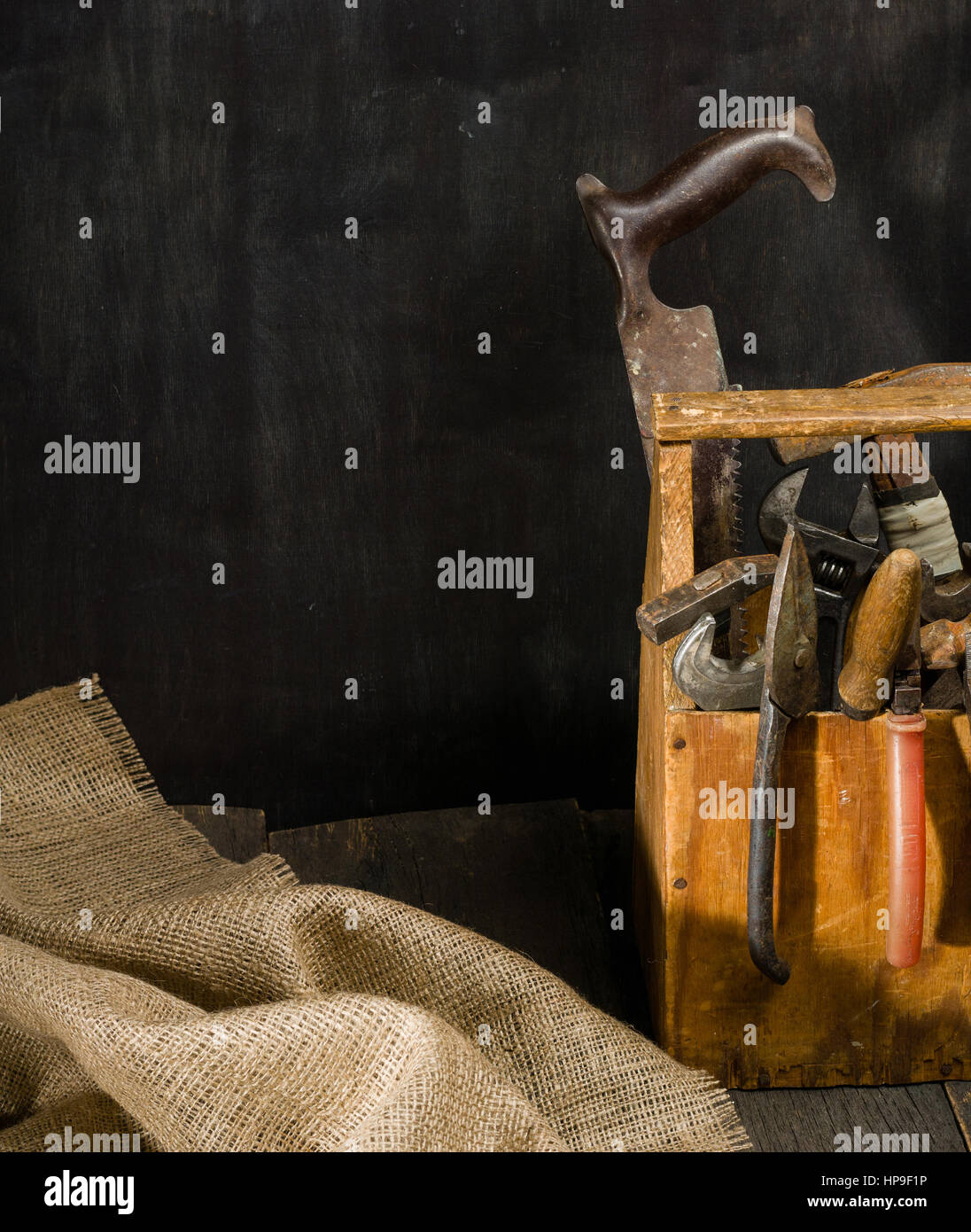 Old used tools in the toolbox. Dark background. spot lighting. Wooden ...