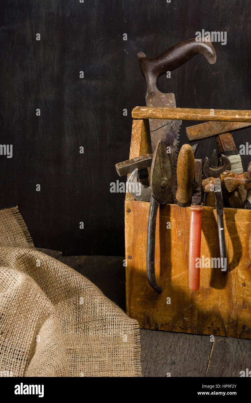 Old used tools in the toolbox. Dark background. spot lighting. Wooden ...