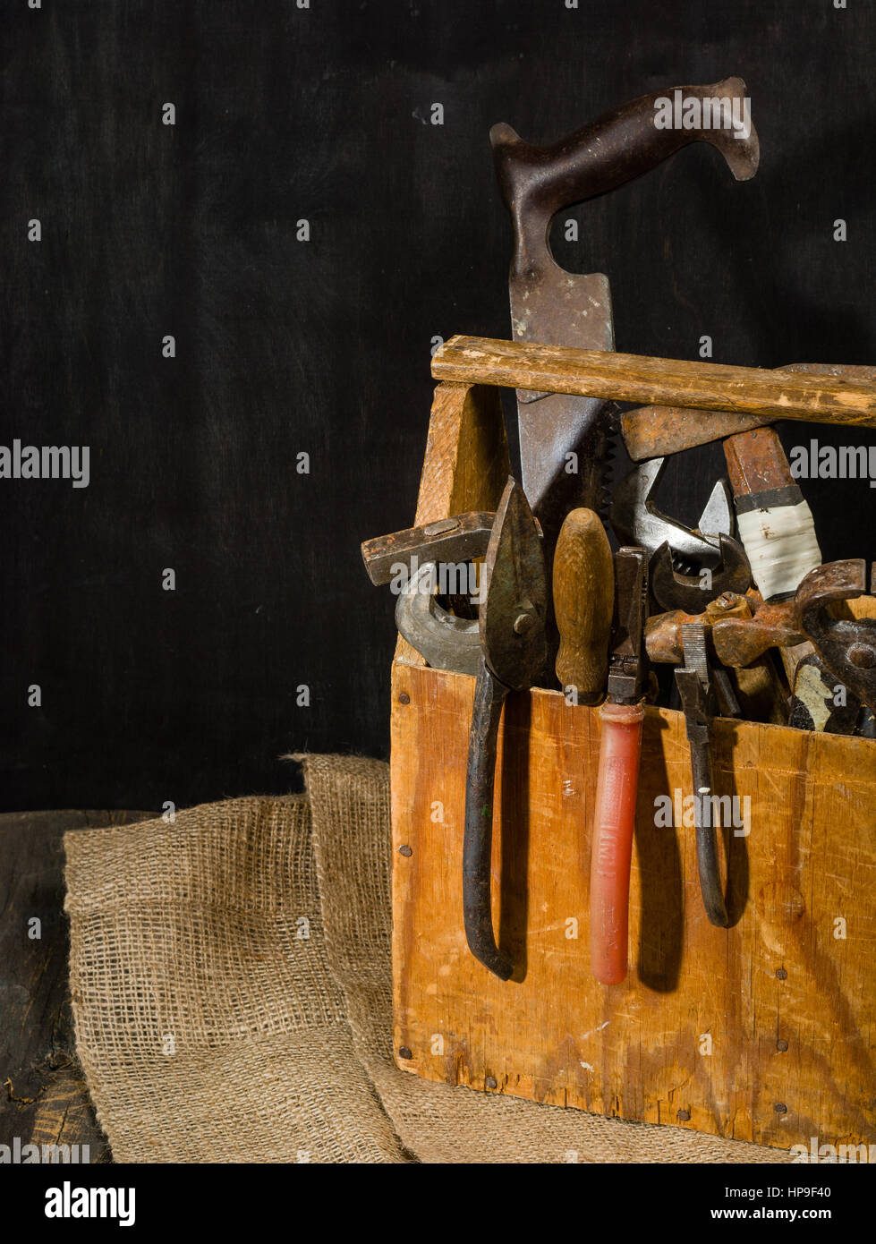 Old used tools in the toolbox. Dark background. spot lighting. Wooden ...