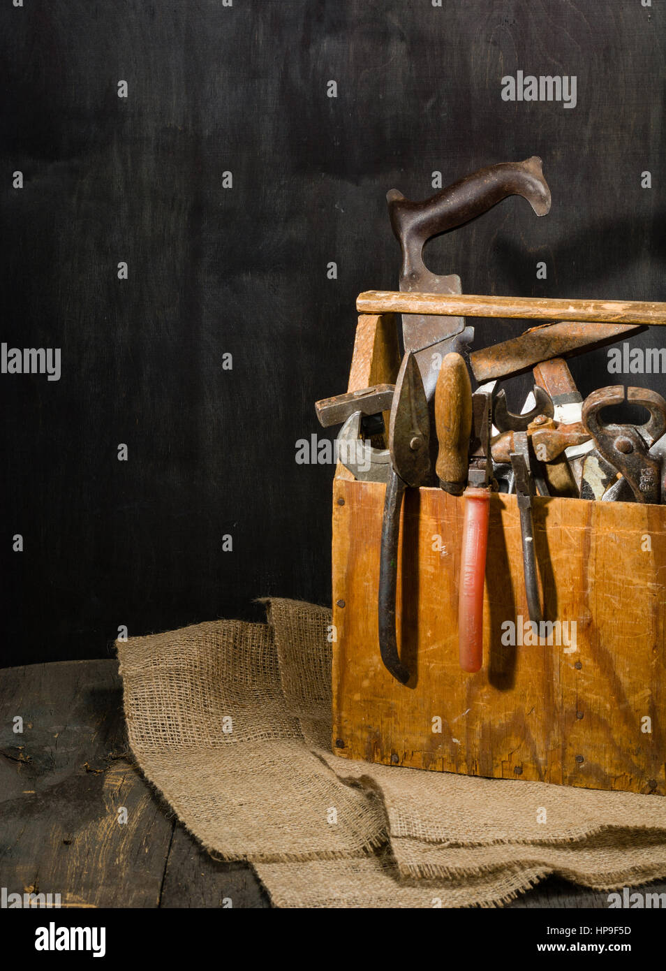 Old used tools in the toolbox. Dark background. spot lighting. Wooden ...