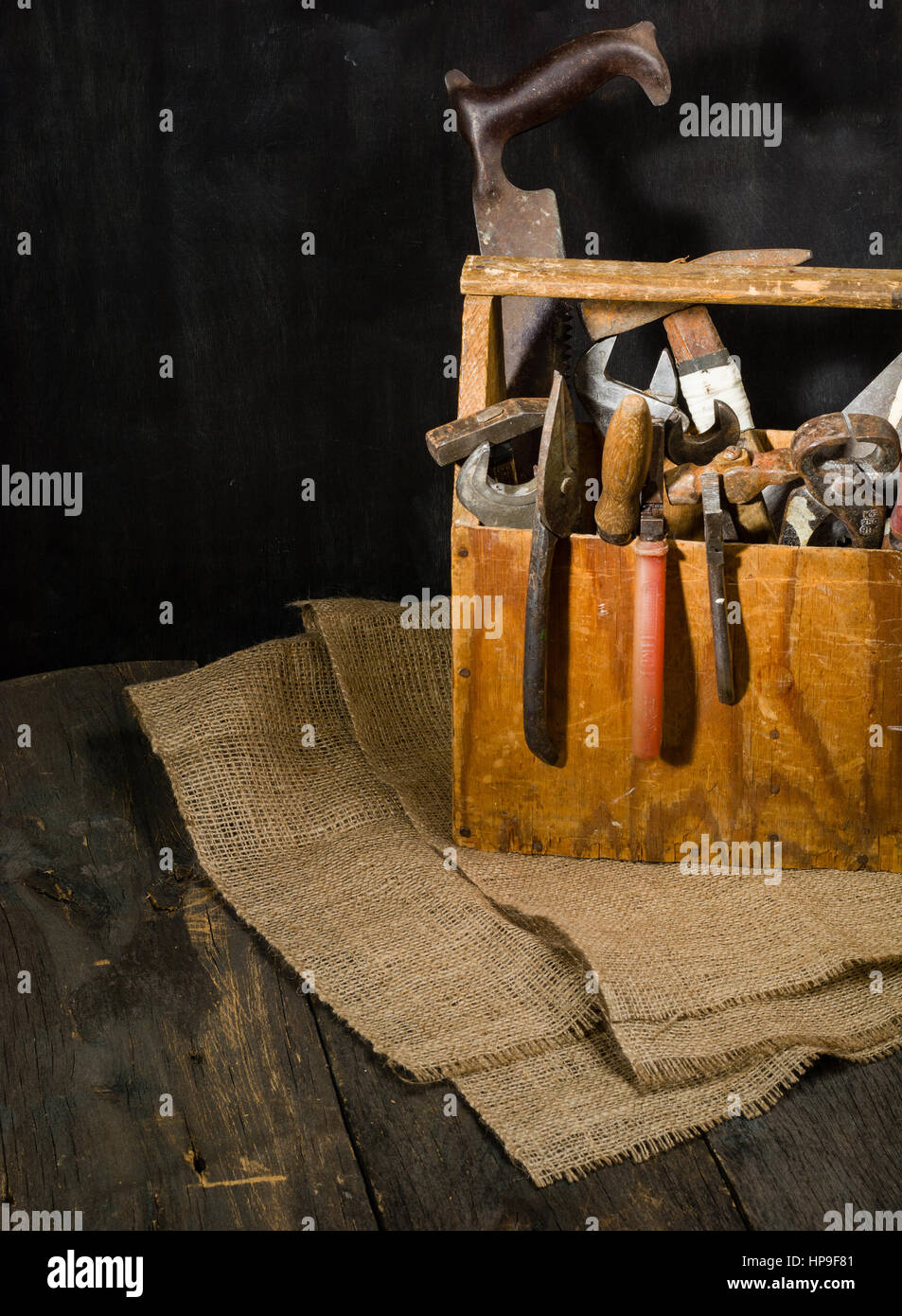 Old used tools in the toolbox. Dark background. spot lighting. Wooden ...