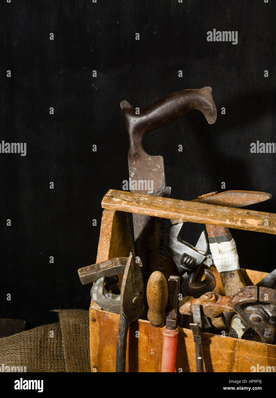Old used tools in the toolbox. Dark background. spot lighting. Wooden ...