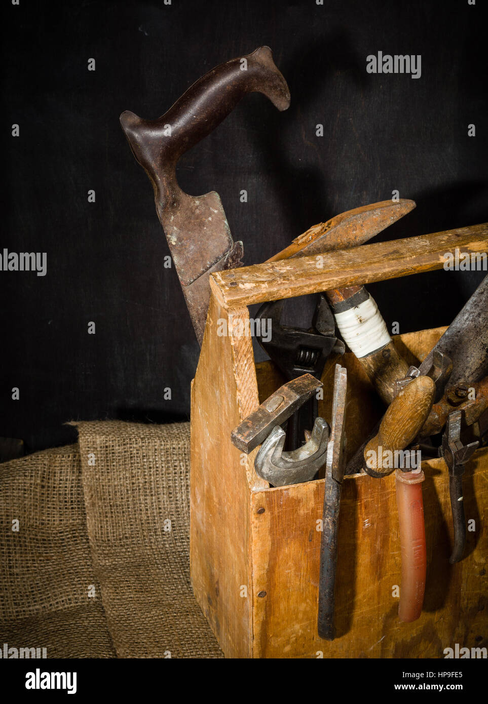 Old used tools in the toolbox. Dark background. spot lighting. Wooden ...