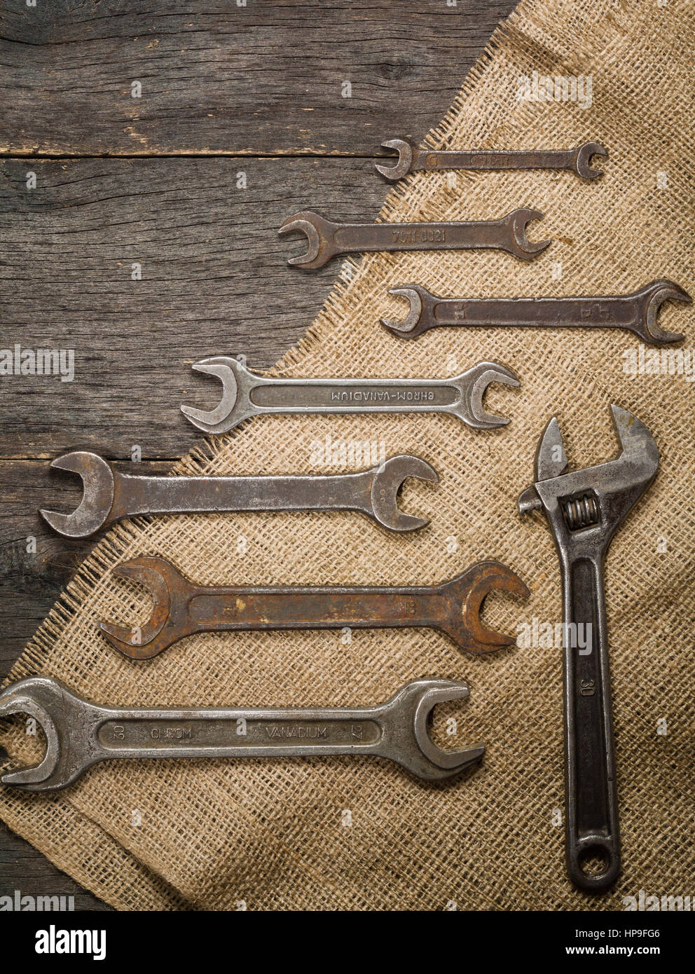 old and rusty spanners on a background of a wooden table and sacking ...