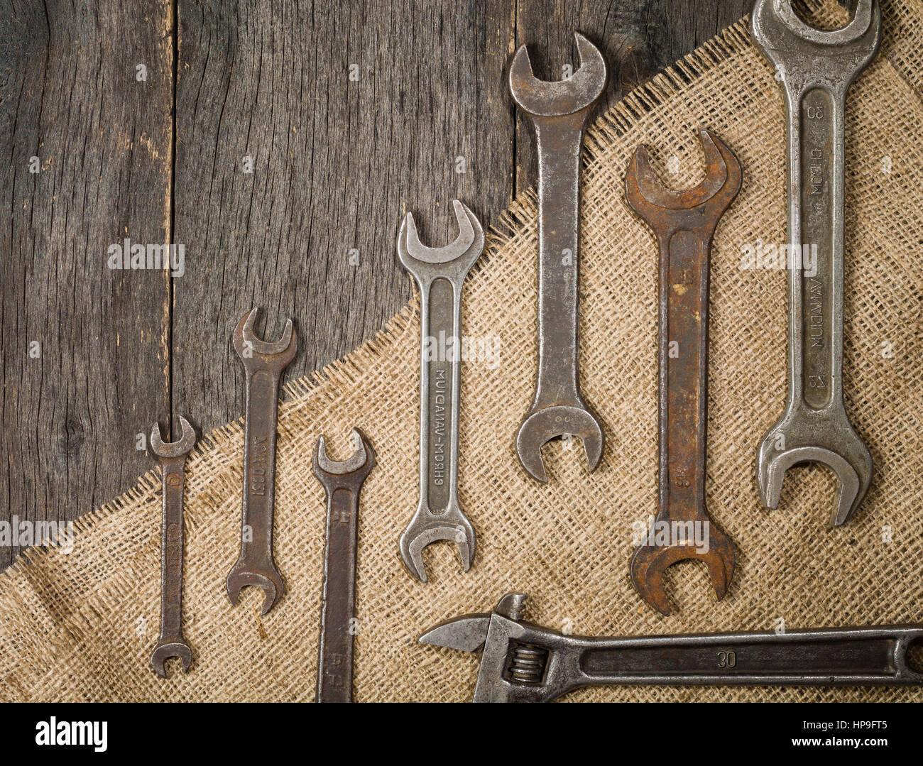 old and rusty spanners on a background of a wooden table and sacking ...