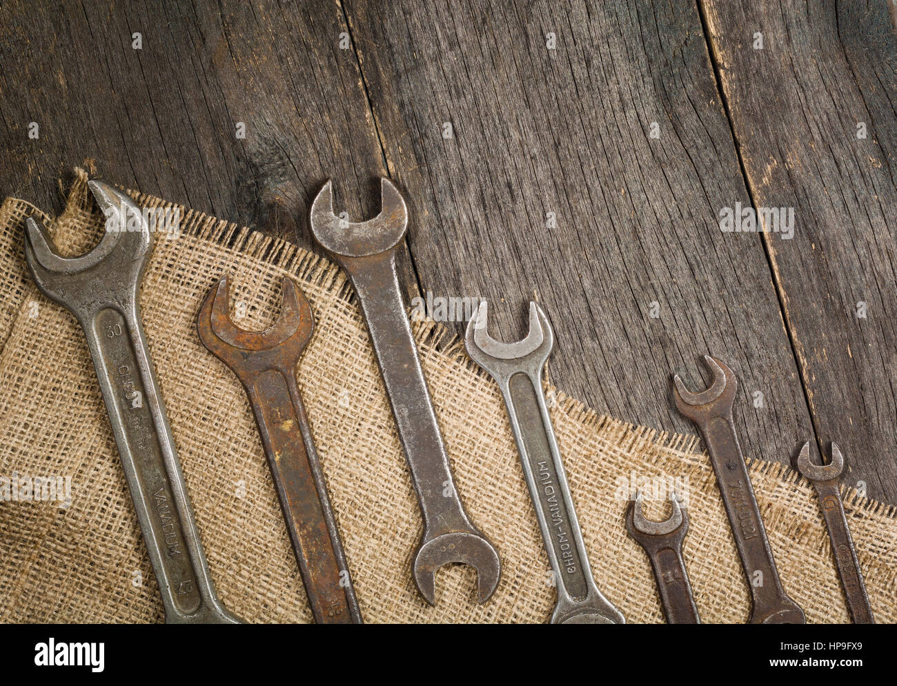 old and rusty spanners on a background of a wooden table and sacking ...