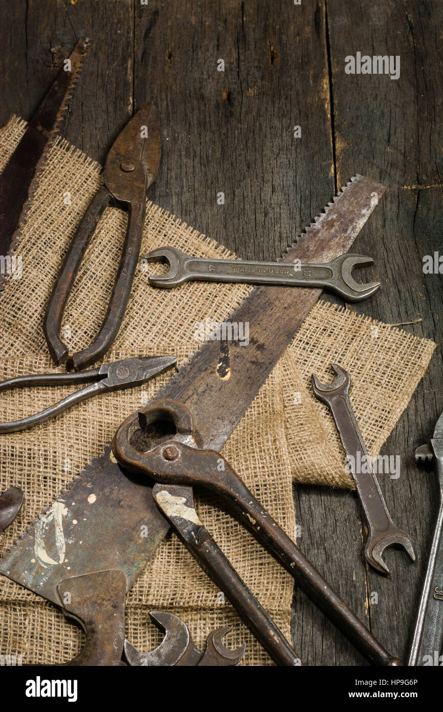 Many old rusty tools scattered on the wooden tstolu. View from above ...