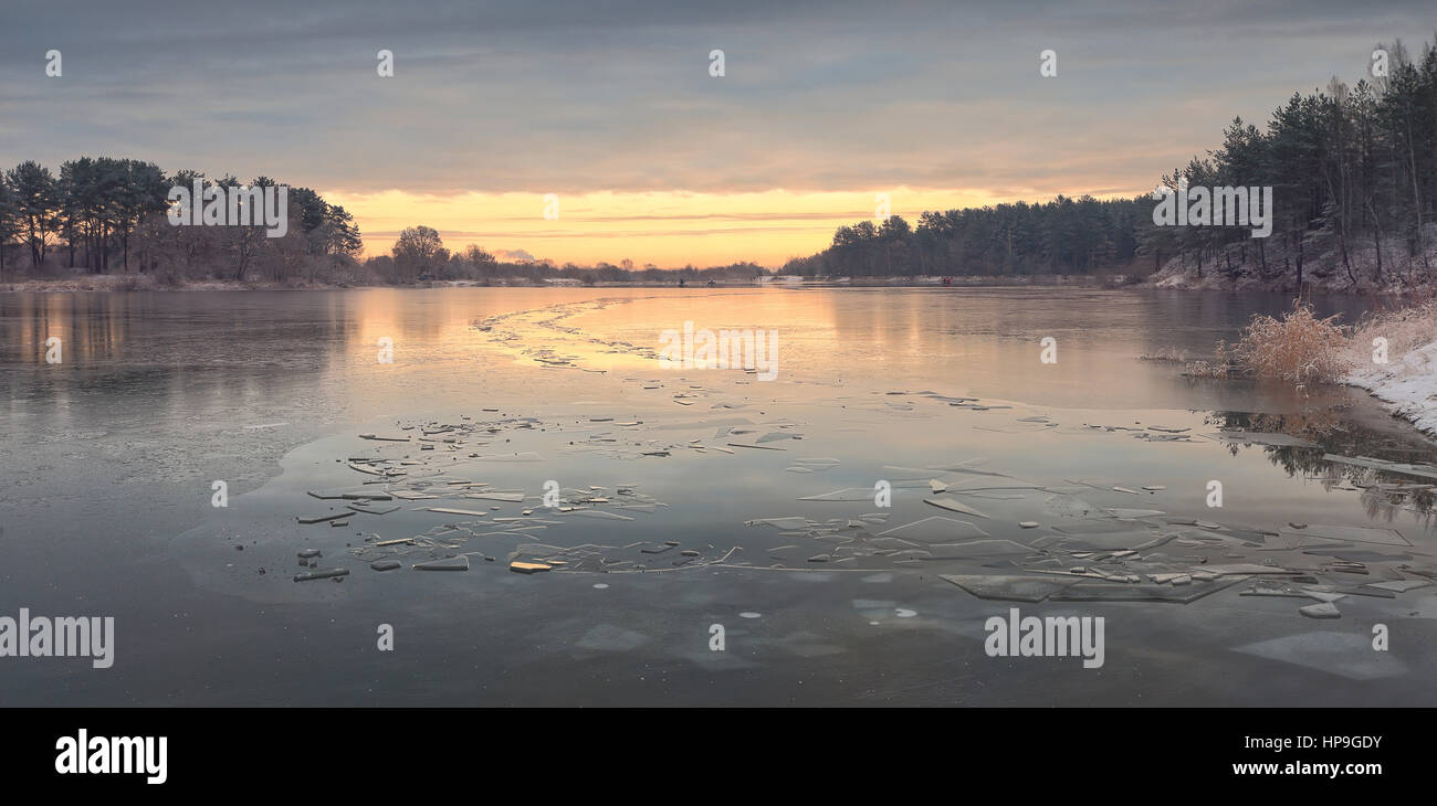 Autumn sunrise above frozen lake. First transparent ice covering lake ...