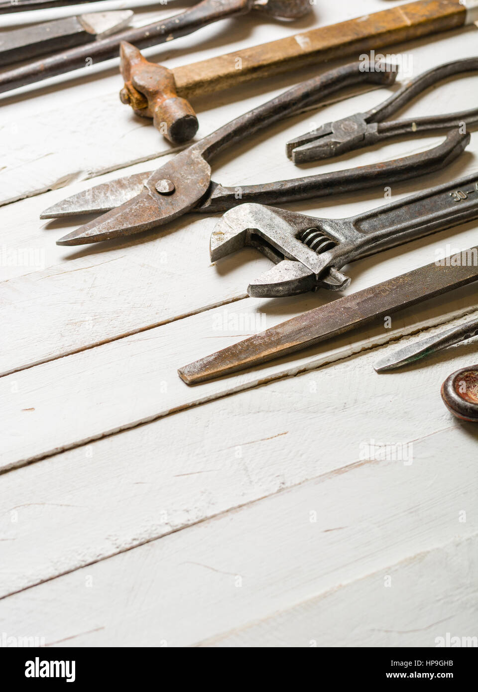 Many old rusty tools scattered on the wooden tstolu. View from above ...