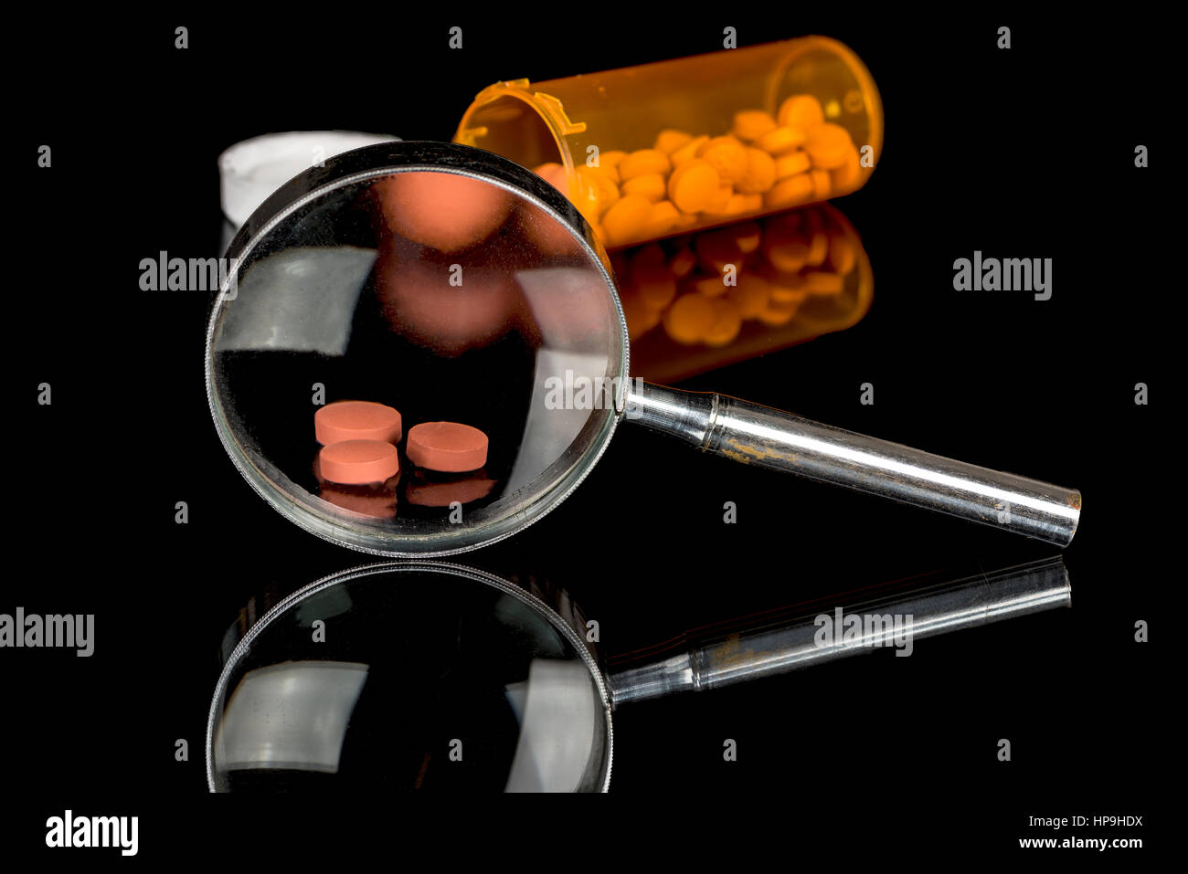 Large magnifying glass and bottle of pills Stock Photo - Alamy