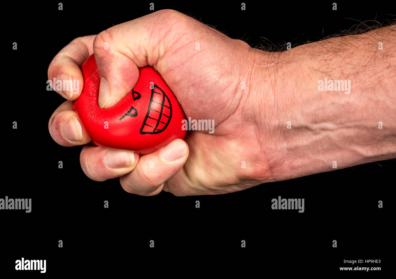 Red stress ball with a mean face is squeezed in a hand Stock Photo - Alamy