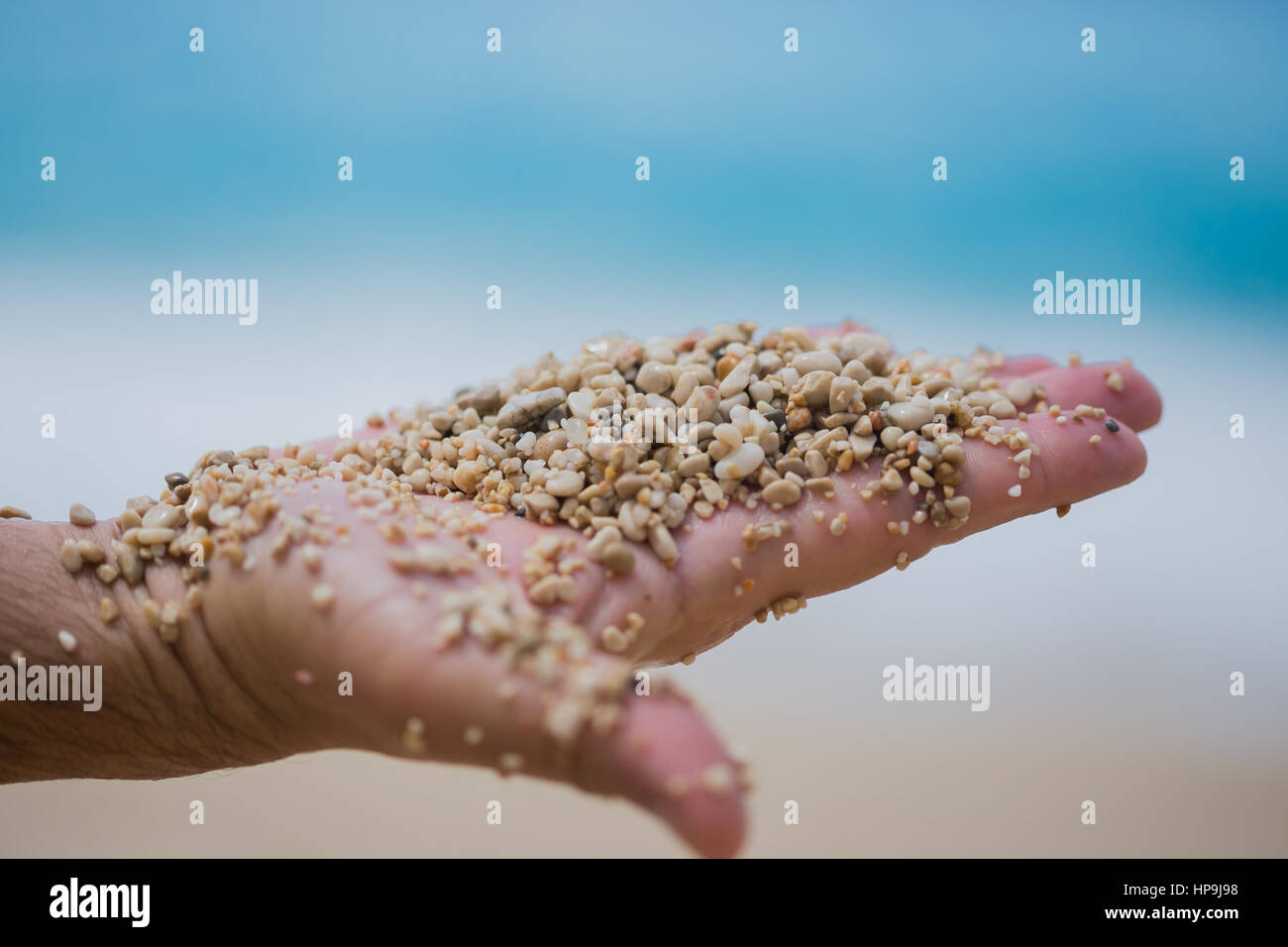 man open hand holding pebble and sand of mixed white biege and ...