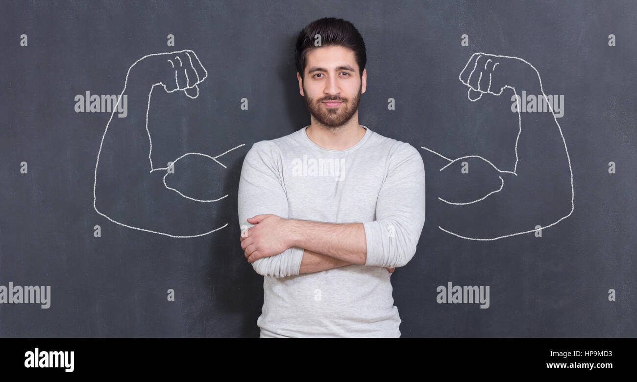 Young man against the background of depicted muscles on chalkboard ...