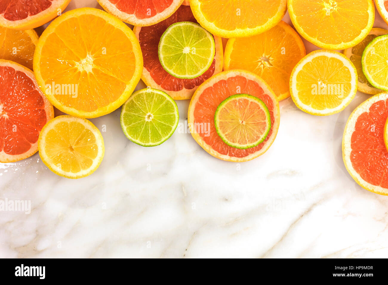 Vibrant juicy citrus fruits on a white marble texture with copy space ...