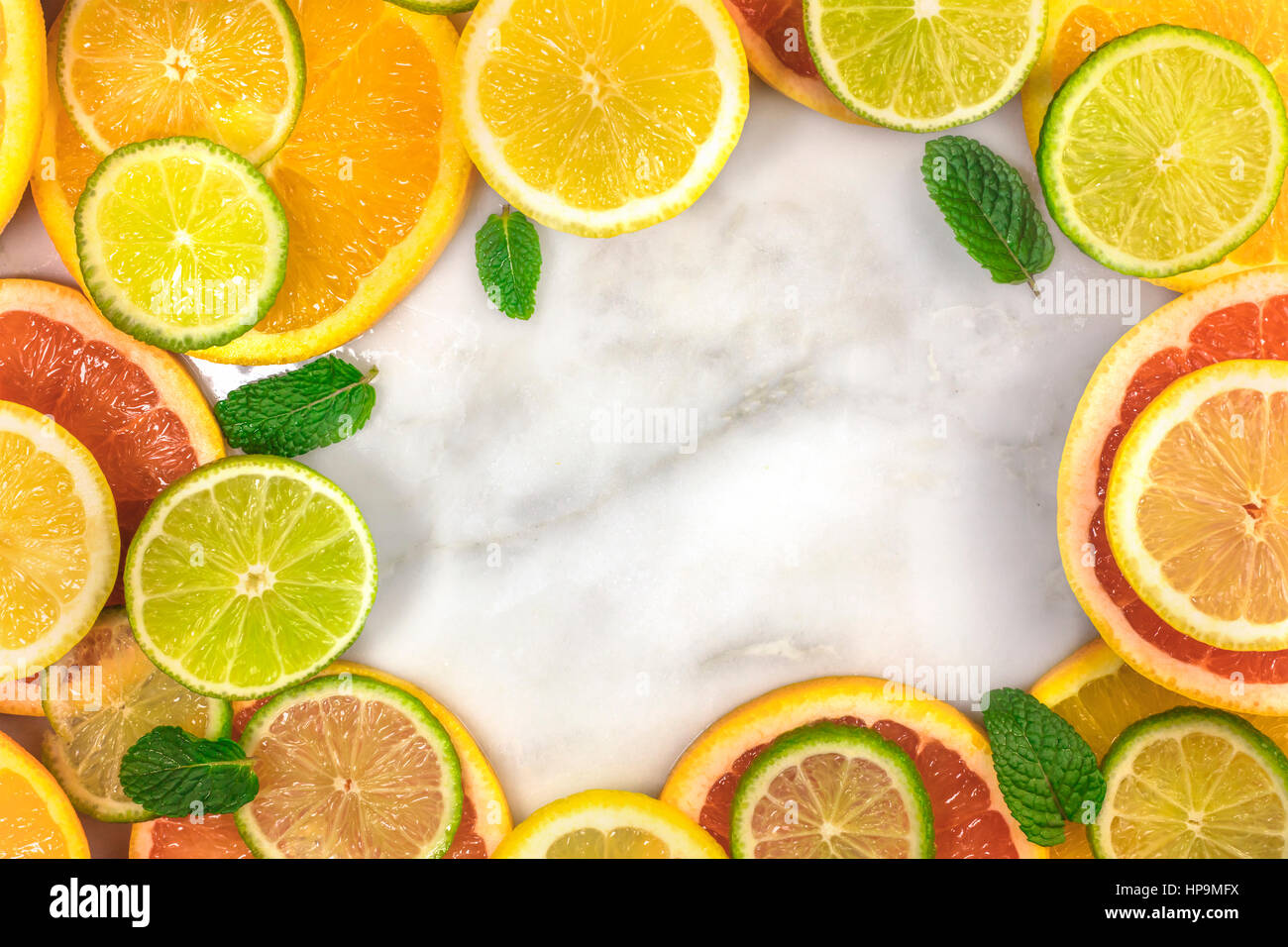 A vibrant frame made up of juicy citrus fruits, on a white marble ...
