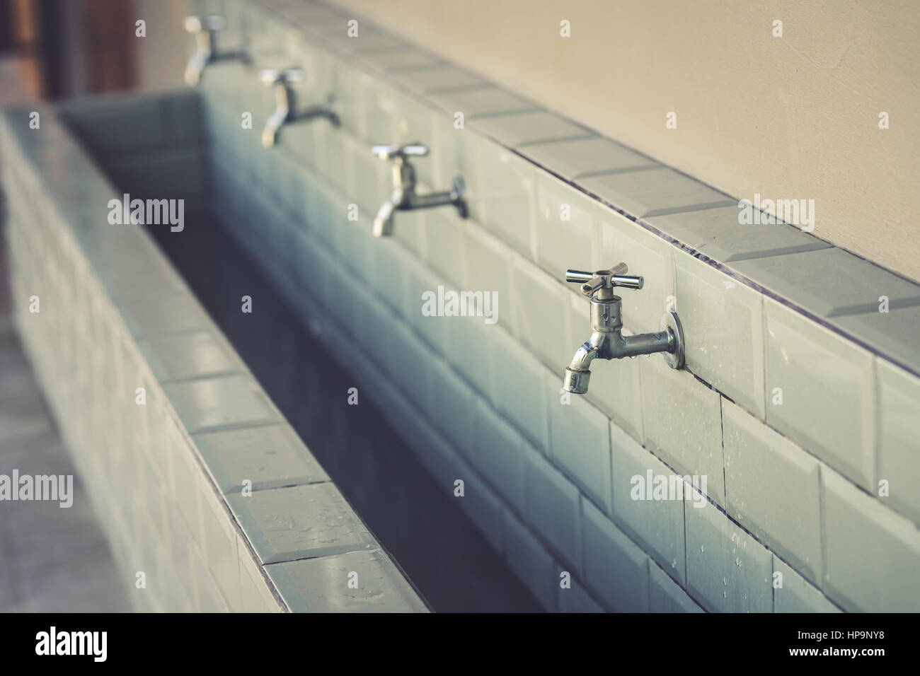row of steel taps into a large bathroom Stock Photo - Alamy